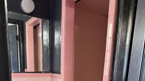 Casa de banho com uma pia branca, azulejos cor-de-rosa e porta preta.