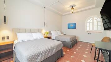 Quarto com duas camas, uma mesa de jantar e janela com vista.