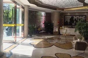 Um saguão de hotel com balcão de recepção, área de estar e piso estampado.