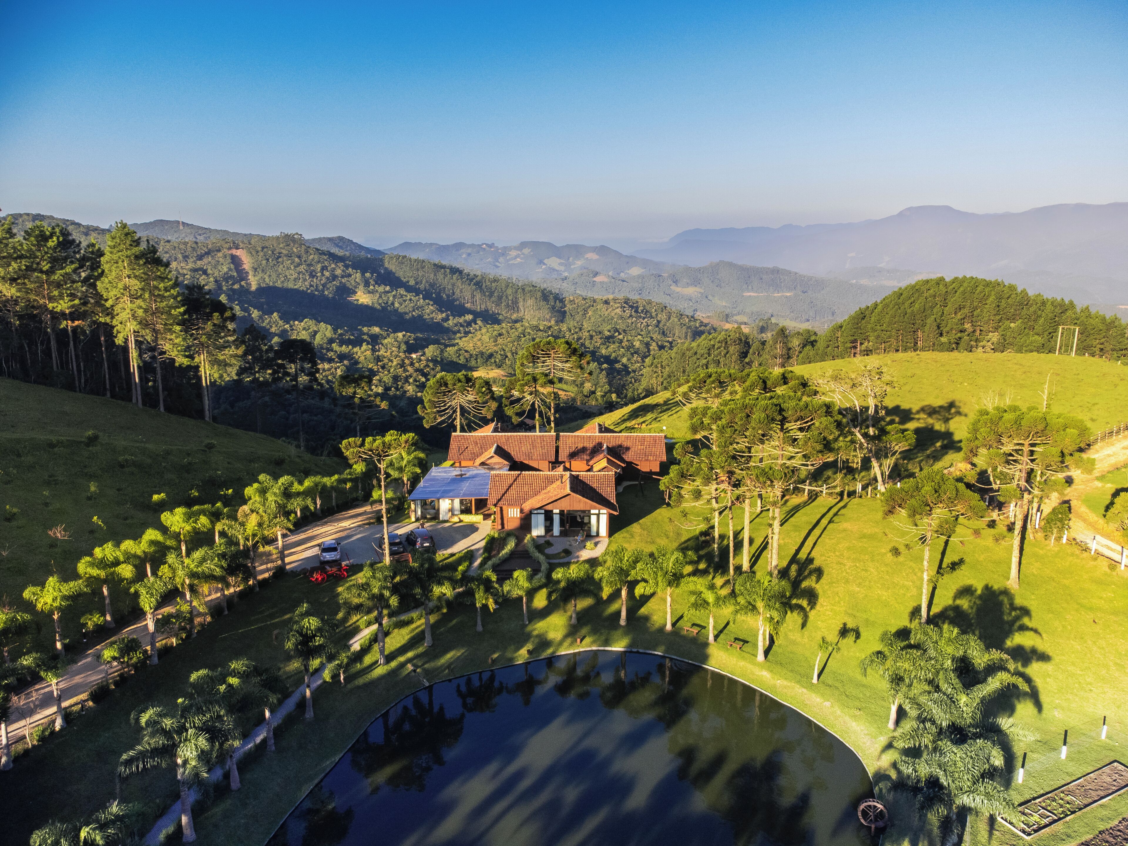 Uma casa com piscina, rodeada por uma paisagem exuberante e montanhas ao longe.