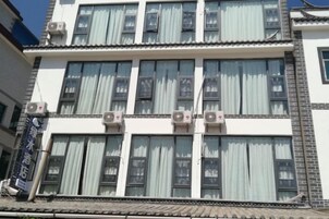 Um edifício com vários andares, unidades de ar condicionado, janelas amplas com cortinas e telhado cerâmico.