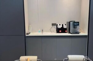 Um banheiro moderno com pia, máquina de café e porta-toalhas.