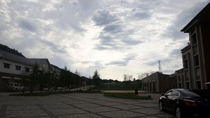 Pátio com edifícios, um carro e céu nublado.