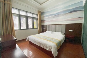 Quarto com cama, escrivaninha, janela com cortinas e um quadro na parede.