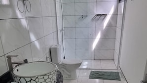 Casa de banho com lavatório de mármore, sanita e zona de duche.