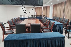 Uma sala de conferências com uma mesa comprida, várias cadeiras e uma tela de projeção.