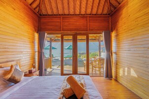Quarto de cabana de madeira com uma cama, uma janela e vista para área de estar externa.