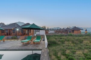 Um resort com piscina, cadeiras de descanso e vista para as montanhas.