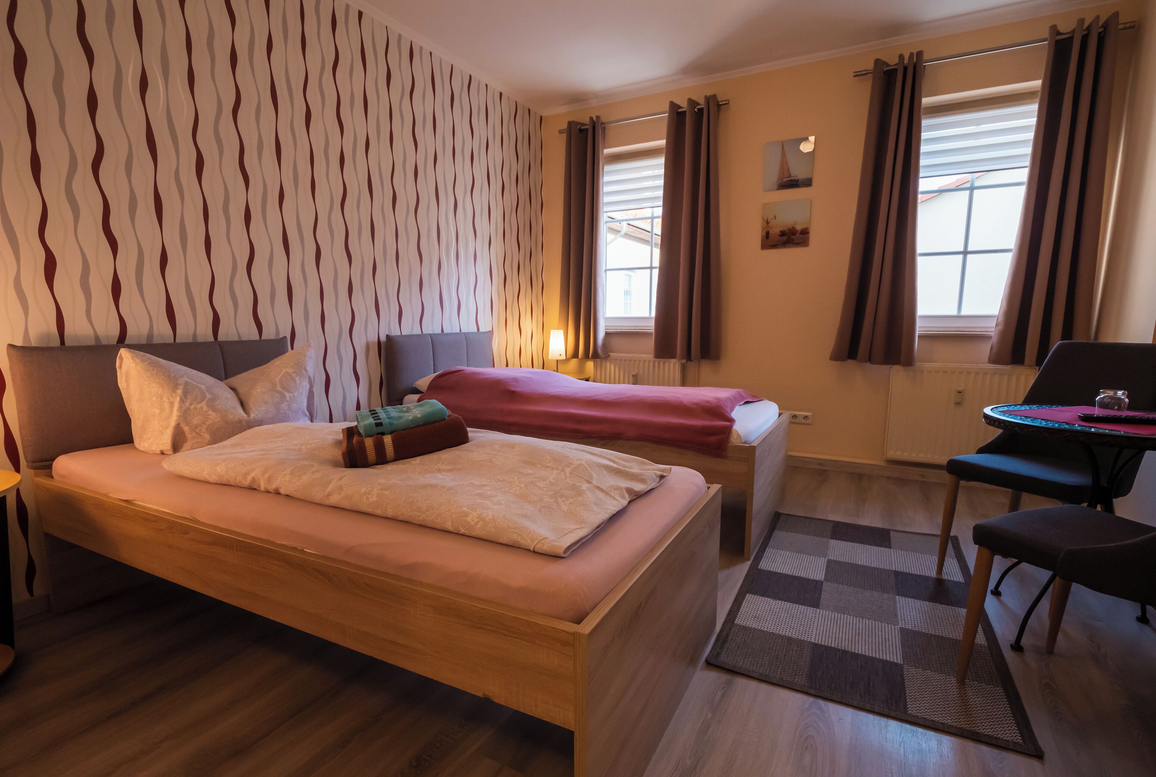 Quarto com cama de madeira, duas mesas de cabeceira, escrivaninha e uma cadeira.