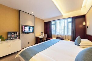 Quarto de hotel com cama grande, escrivaninha, televisão e armário.