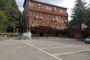 Um hotel com vários andares e arquitetura tradicional, com um pátio e área de entrada coberta.