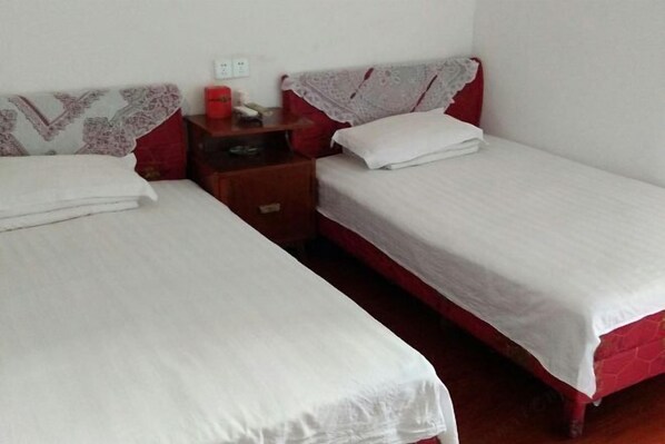 Quarto com duas camas, uma mesa de cabeceira de madeira e uma cabeceira vermelha.