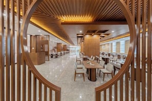 Um restaurante moderno com área de refeições central, painéis de madeira e design de teto curvo.