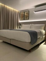 Quarto moderno com uma cama grande, ar condicionado na parede e uma luminária de teto.