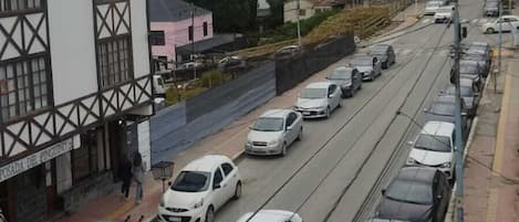 Uma rua com carros estacionados na lateral, edifícios com arquitetura tradicional e céu claro.