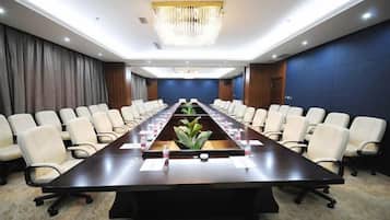 Uma sala de conferências com uma mesa comprida, cadeiras e um lustre.