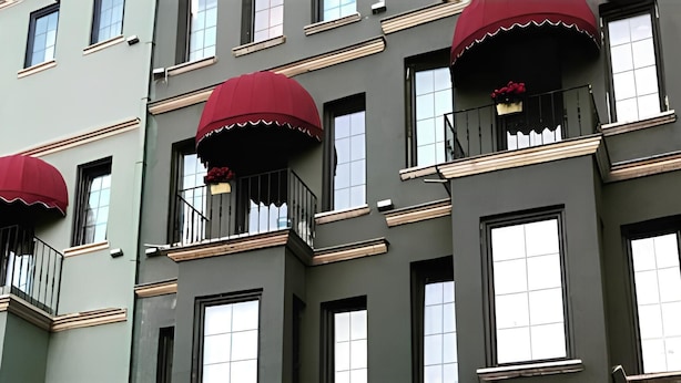 Um edifício com várias andares e varandas, cada uma com um toldo vermelho.