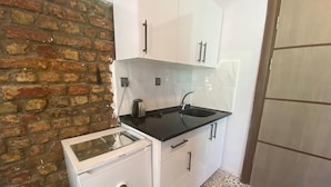 Uma cozinha compacta com armários brancos, bancada preta e tapete estampado.