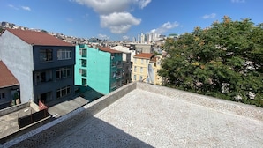 Terraço no telhado com azulejos estampados, edifícios vizinhos e céu azul límpido.