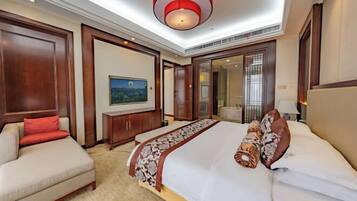 Quarto de hotel com uma cama grande, um sofá, uma escrivaninha e um quadro na parede.