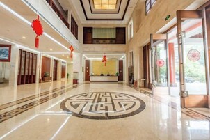 Um saguão de hotel com uma mesa de recepção, um padrão de piso decorativo grande e vista para o exterior pela entrada.