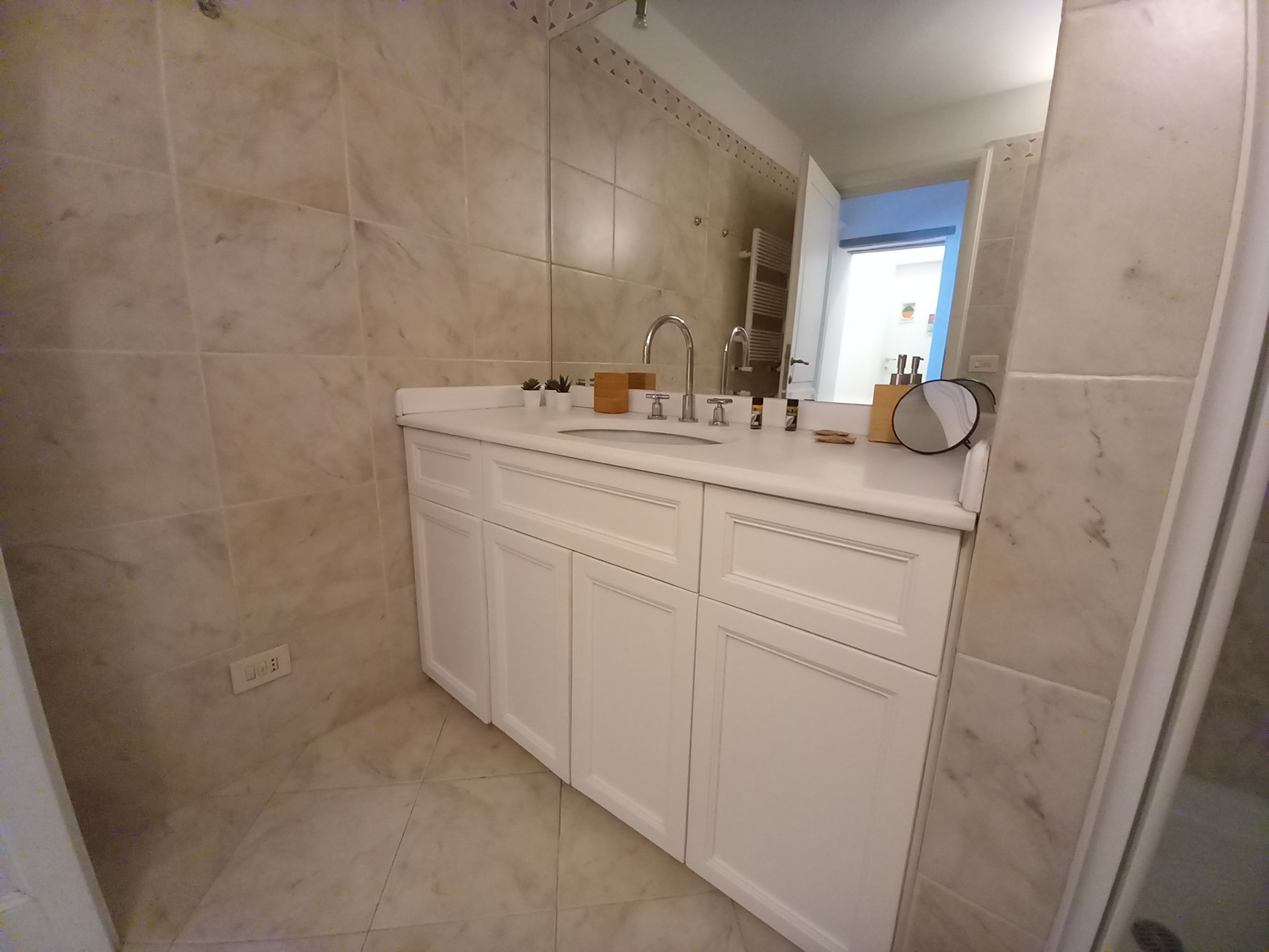 Uma casa de banho com lavatório branco, um lavatório e um espelho.
