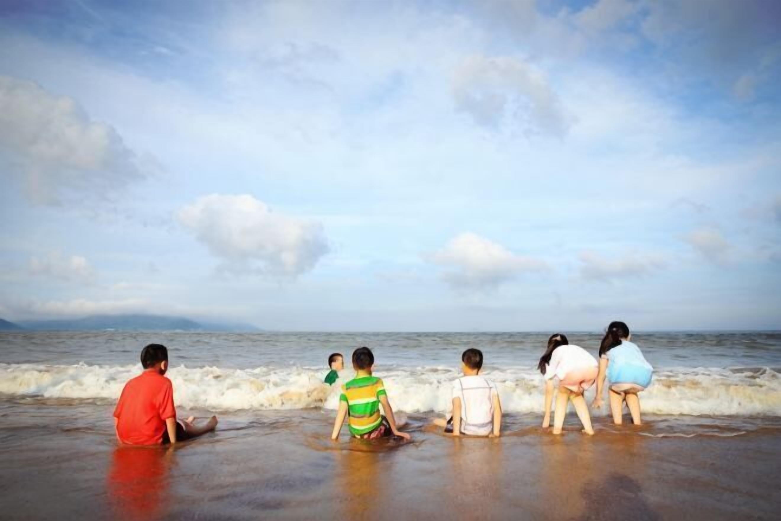 Um grupo de pessoas sentadas na praia, olhando para o oceano.