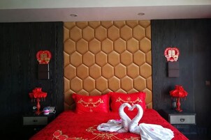 Quarto de hotel com uma cama grande, cabeceira com padrão geométrico e duas mesas de cabeceira com objetos decorativos.