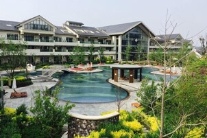 Hotel com piscina, área de estar externa e jardim paisagístico.