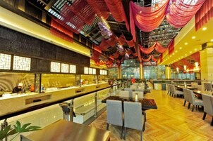 Restaurante com pé-direito alto, decoração moderna e um balcão central.