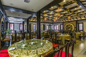 Restaurante com mesas redondas, tapetes vermelhos e decoração tradicional.