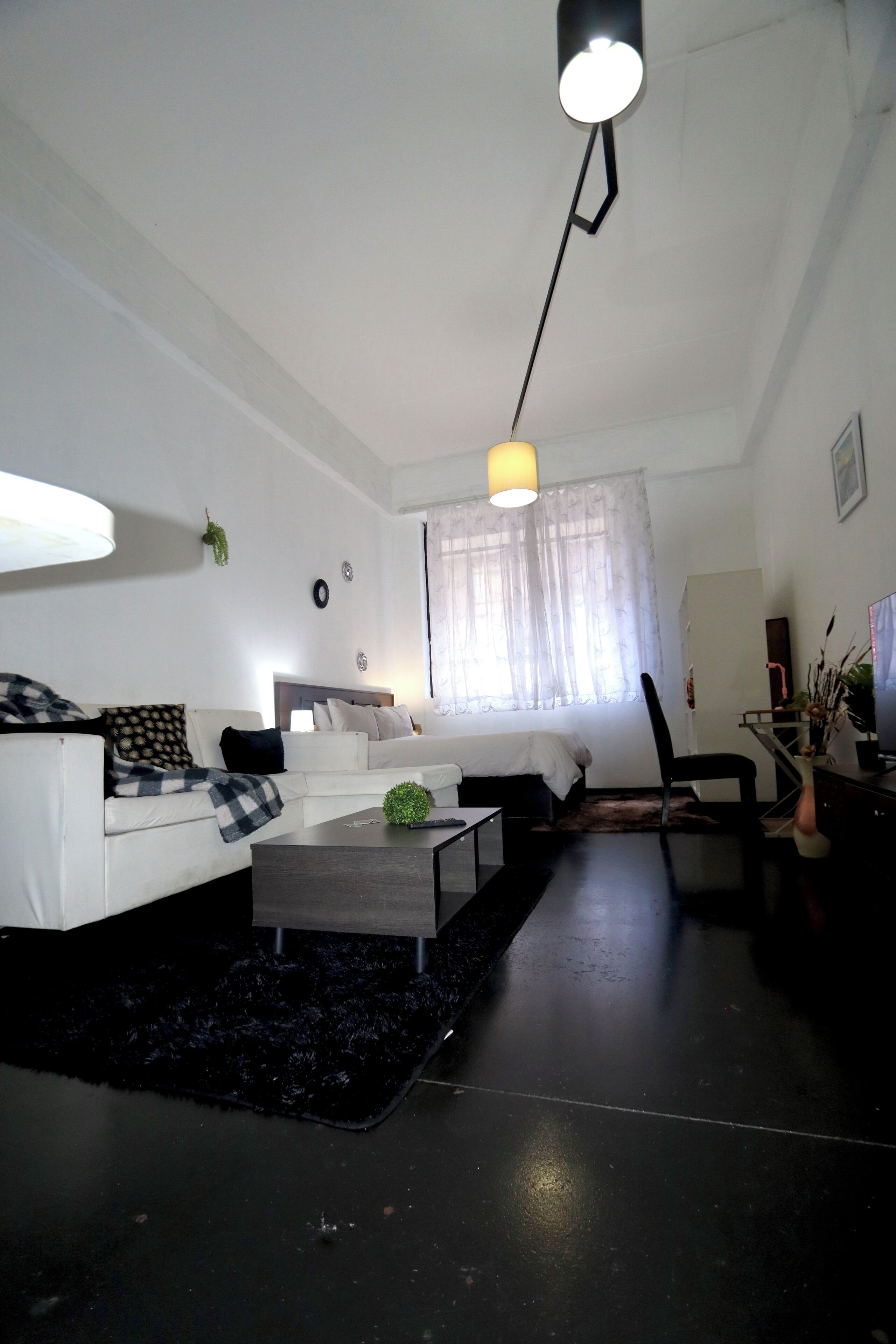Uma sala de estar moderna e bem iluminada, com sofá, mesa de centro e televisão.
