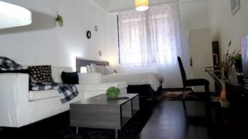 Uma sala de estar moderna e bem iluminada, com sofá, mesa de centro e televisão.