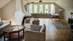 Uma sala de estar ampla, com teto alto, lareira e área de jantar com mesa e cadeiras.