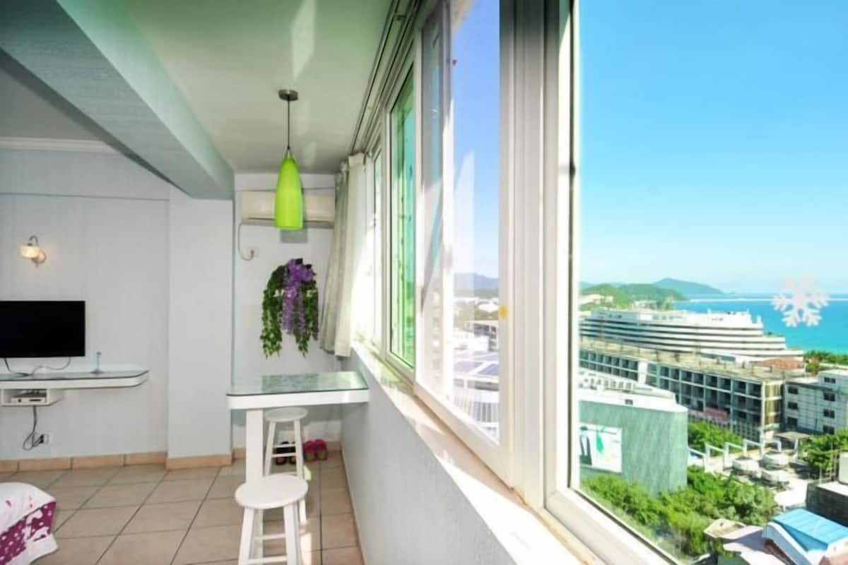 Varanda com vista para um cruzeiro, uma televisão e uma pequena mesa com uma cadeira.