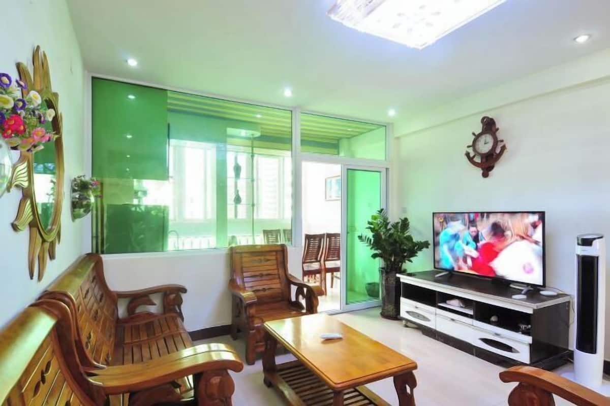 Sala de estar com móveis de madeira, televisão e uma janela grande.