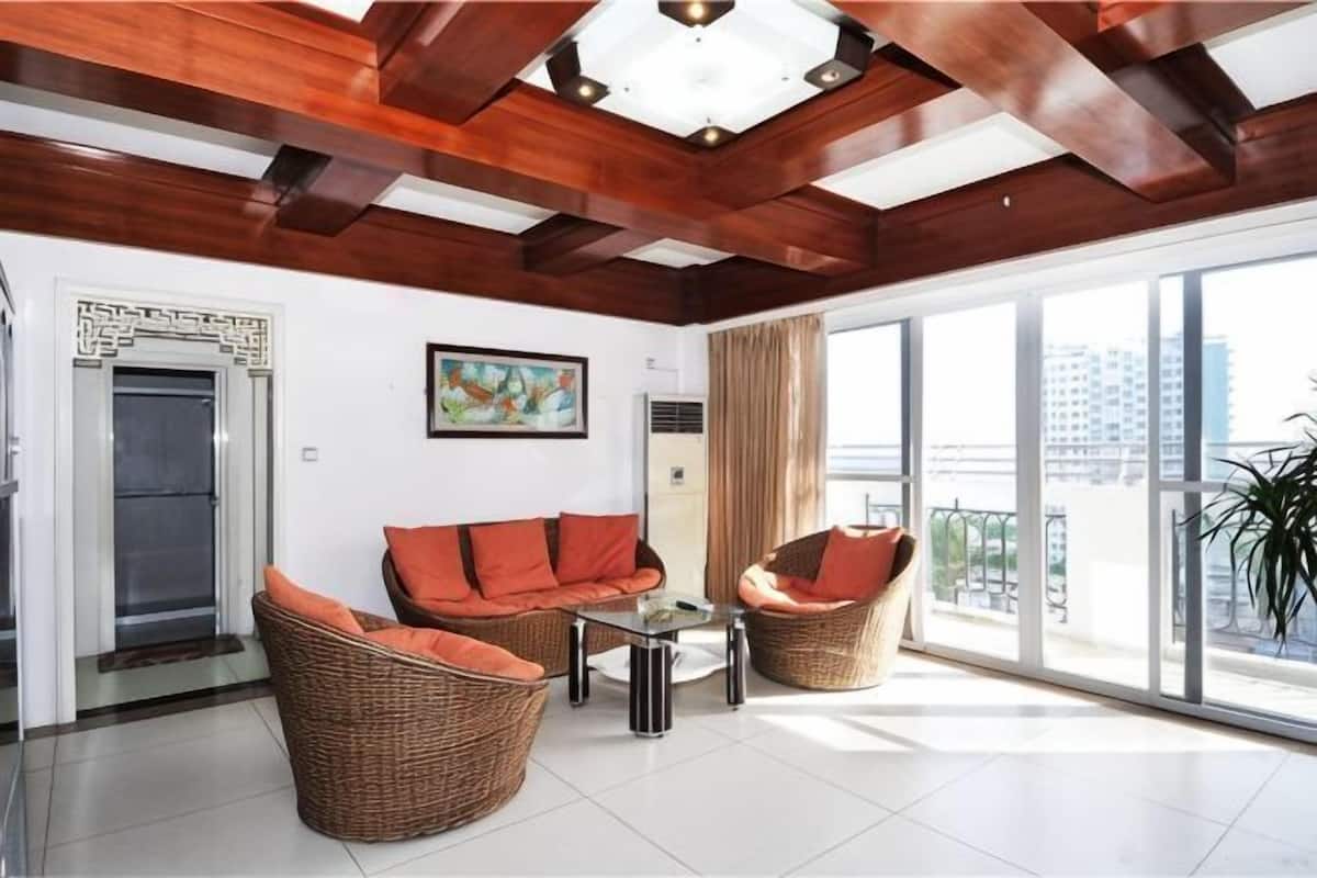 Sala de estar moderna com teto alto, janelas amplas e vista para a cidade.