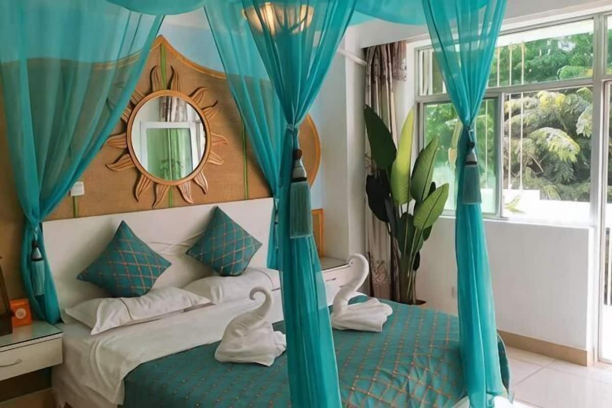 Quarto com cama, espelho e janela.