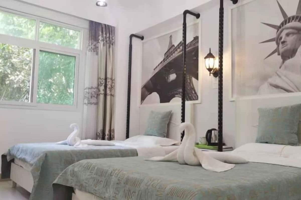 Quarto de hotel com duas camas, cada uma decorada com uma toalha em forma de cisne.