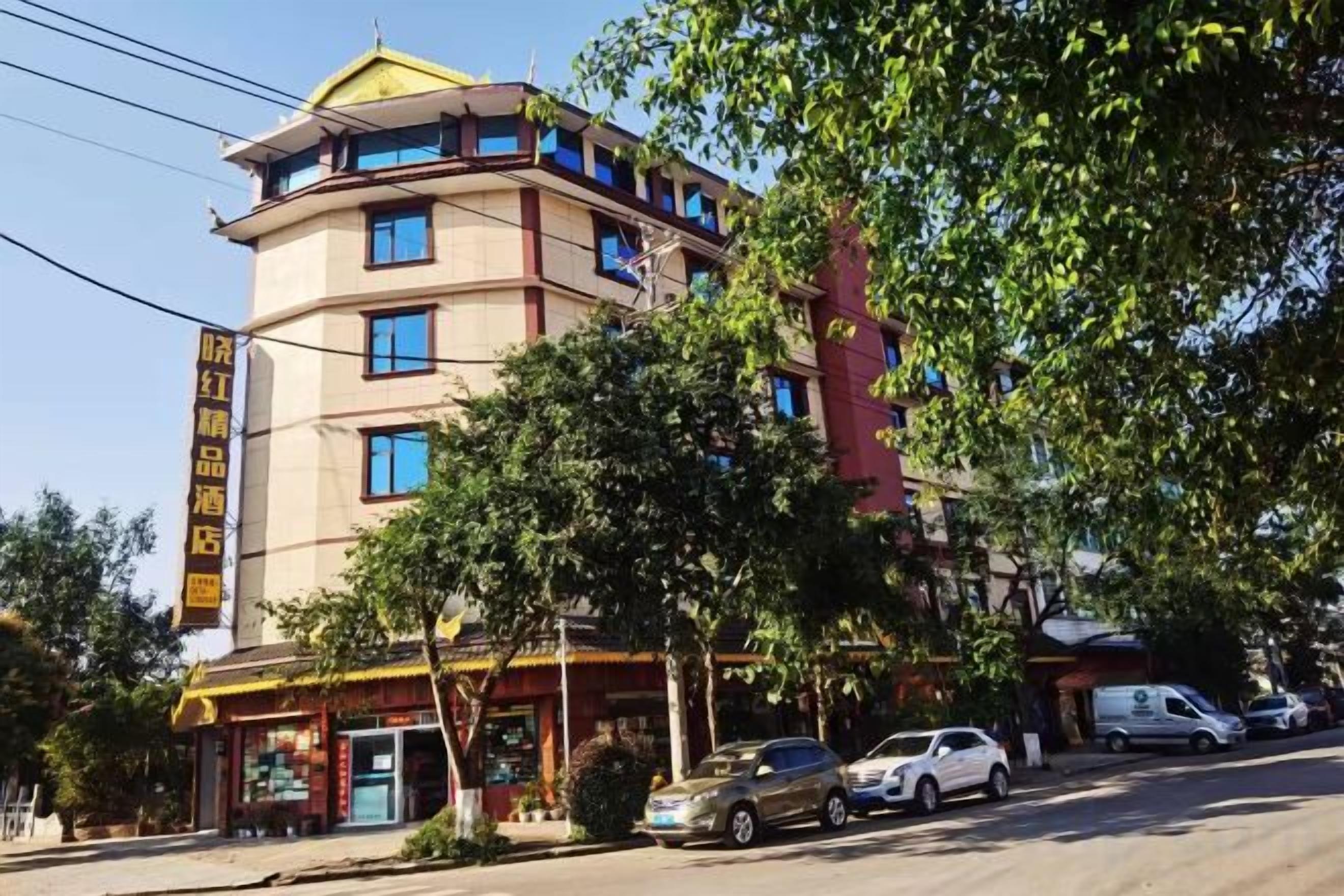 Hotel de vários andares com entrada imponente, restaurante visível e carros estacionados.