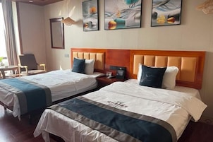 Quarto de hotel com duas camas, cabeceira de madeira, uma cadeira e obras de arte na parede.