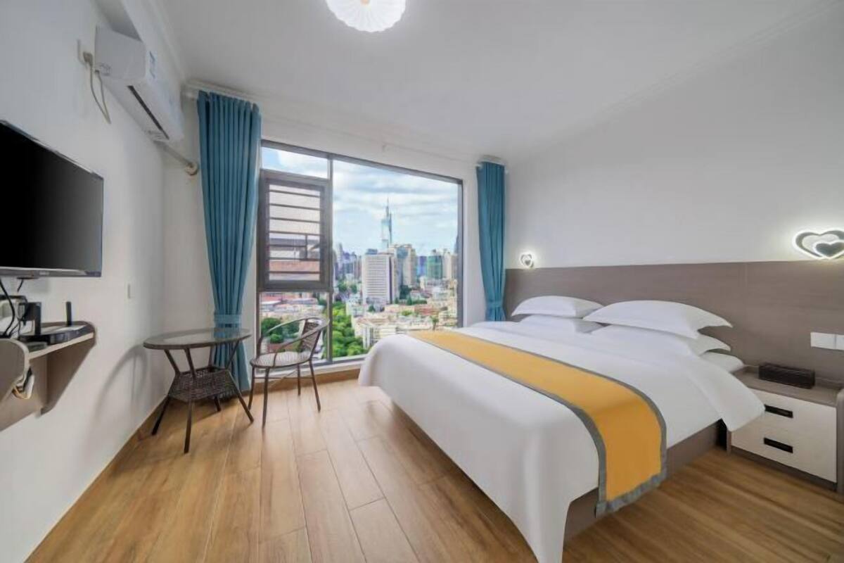 Quarto de hotel com cama, televisão, secretária e cadeira.