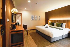 Quarto de hotel com cama, escrivaninha, cadeira, espelho e decoração de parede.