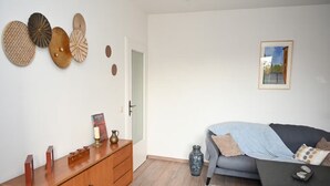 Quarto moderno com cômoda de madeira, sofá cinza e quadro na parede.