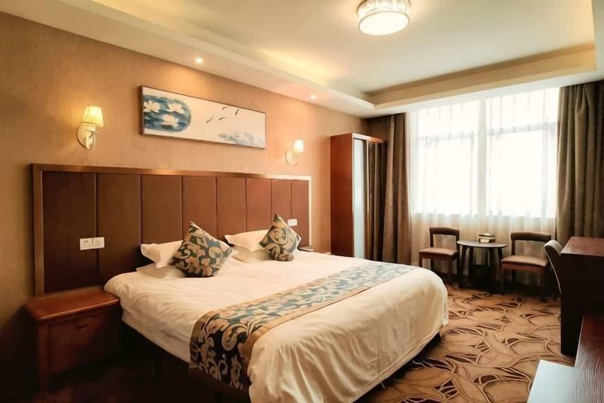 Quarto de hotel com uma cama grande, uma escrivaninha e uma cadeira.