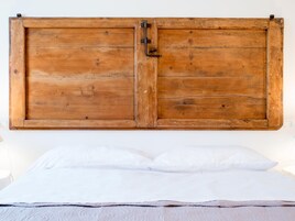 Cama com roupa de cama branca e cabeceira de madeira com fecho.