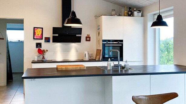 Cozinha moderna com ilha central, luminárias pendentes e vista para o exterior.