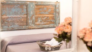 Quarto com parede de painel de madeira rústica, um banco acolchoado e uma cesta de vime com tecido branco.
