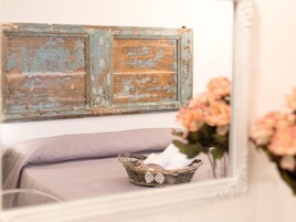 Quarto com parede de painel de madeira rústica, um banco acolchoado e uma cesta de vime com tecido branco.