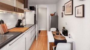 Uma cozinha moderna com armários brancos, bancada de madeira e área de refeições com mesa e cadeiras brancas.